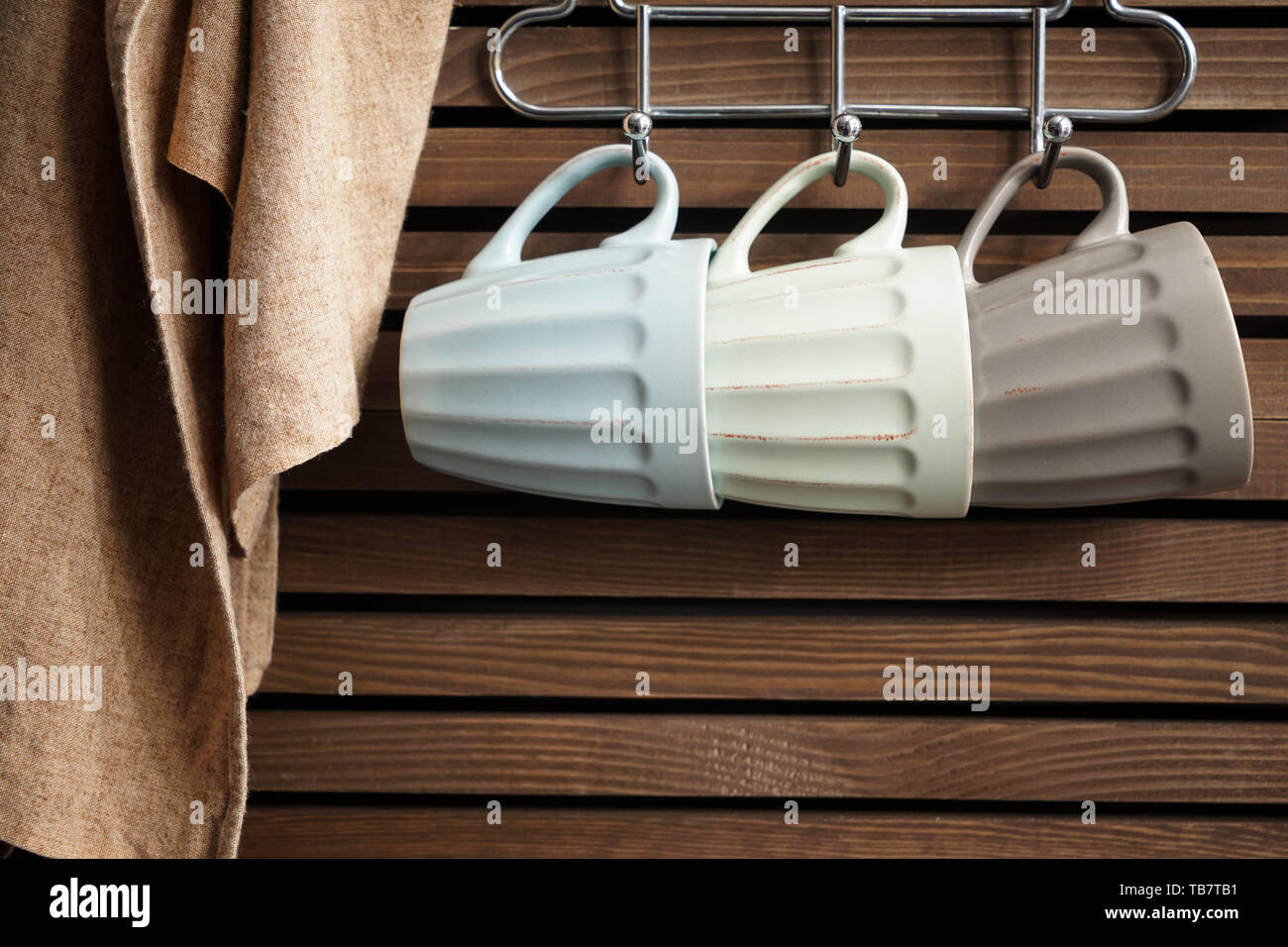 Different tea cups hanging on wooden wall Stock Photo - Alamy
