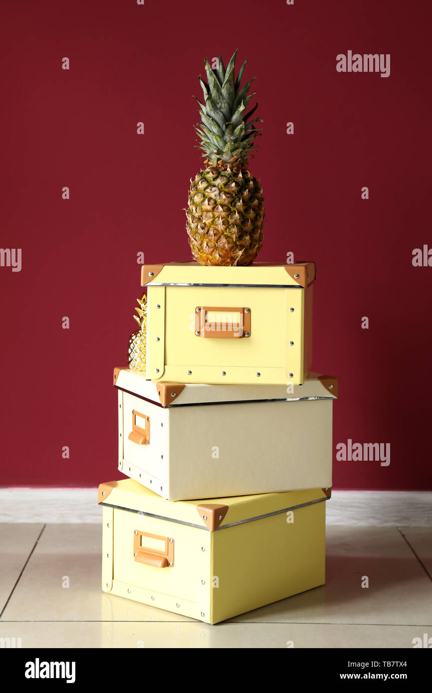 Pineapple with boxes against color wall Stock Photo - Alamy