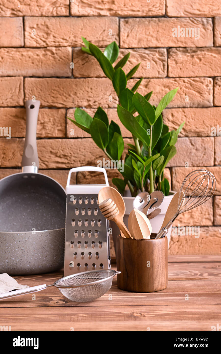 Set of kitchen utensils on table near brick wall Stock Photo - Alamy