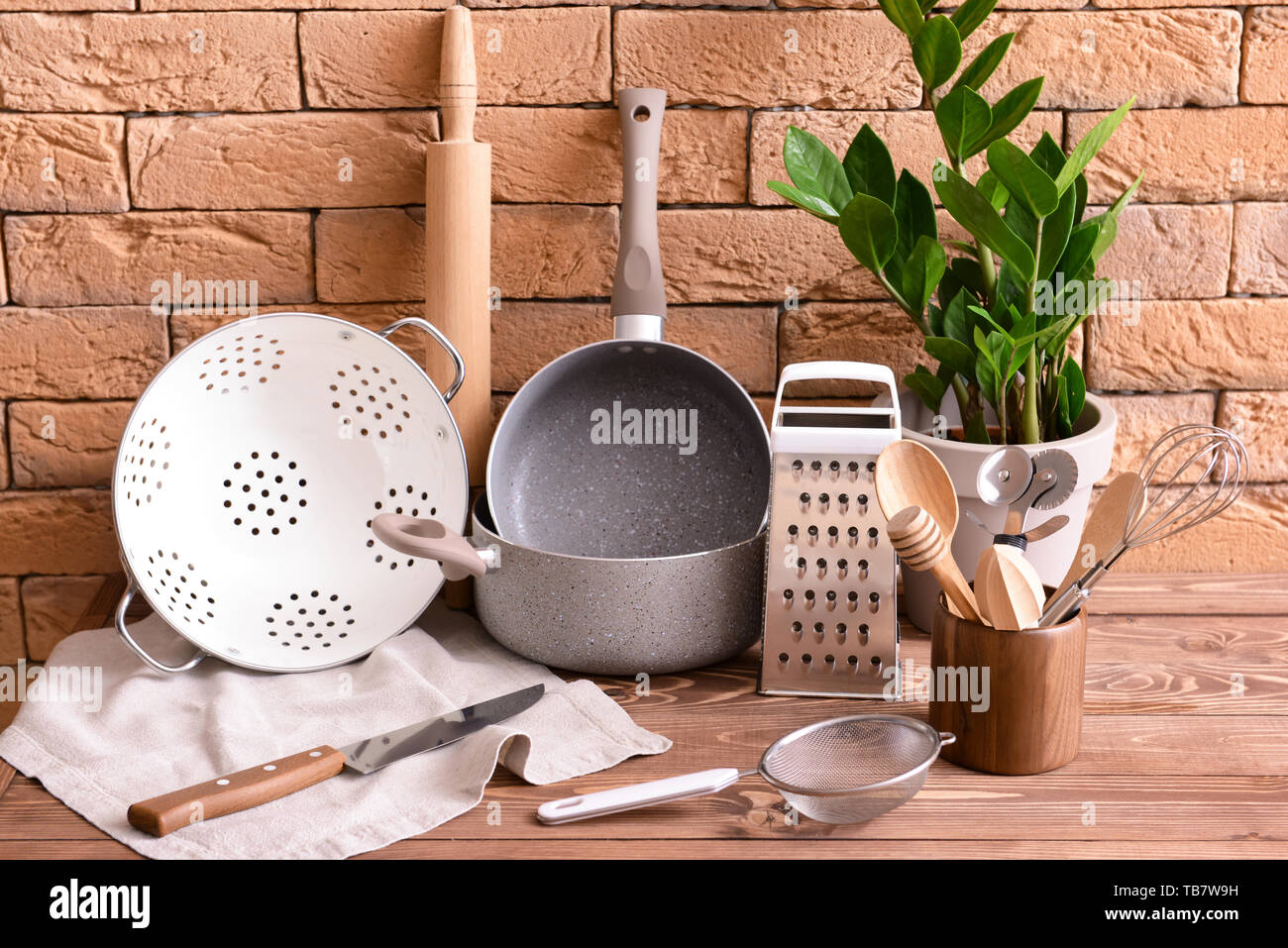 Set of kitchen utensils on table near brick wall Stock Photo - Alamy