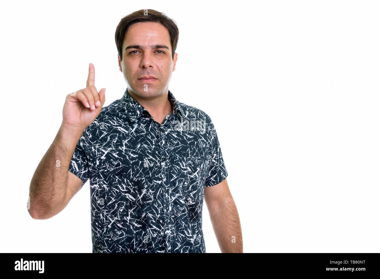 Studio shot of young Persian man pointing finger up isolated against ...