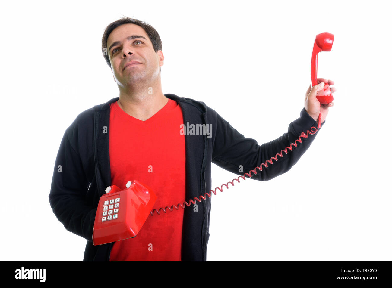 Studio shot of thoughtful young Persian man holding old telephone away ...