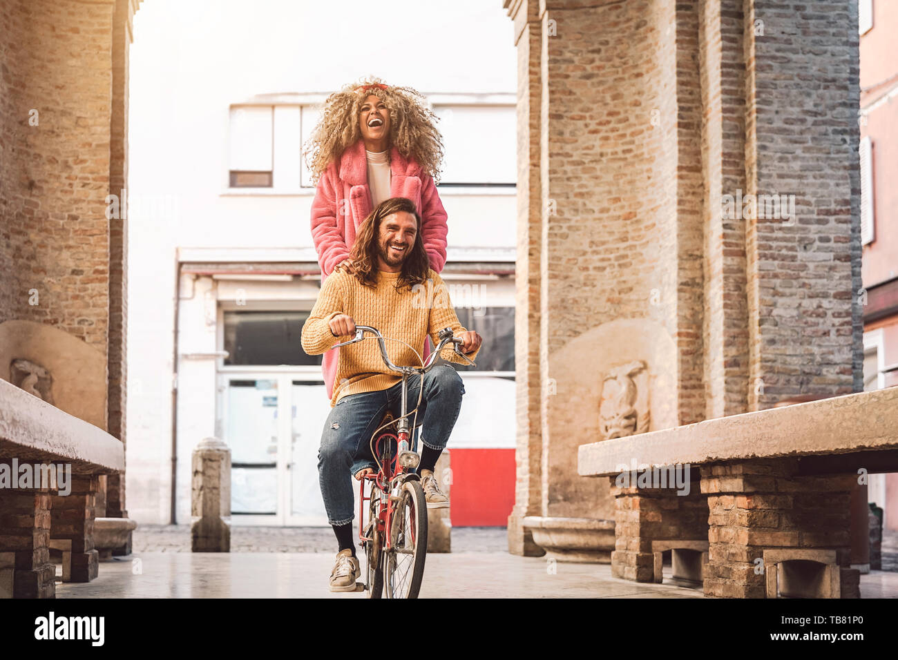 Happy couple going on bicycle in the city center - Young people having ...