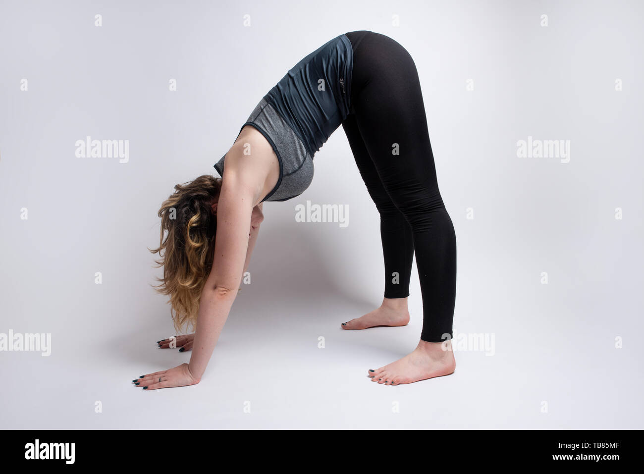 Down dog yoga pose done by flexible blonde woman. Sport can be done at ...