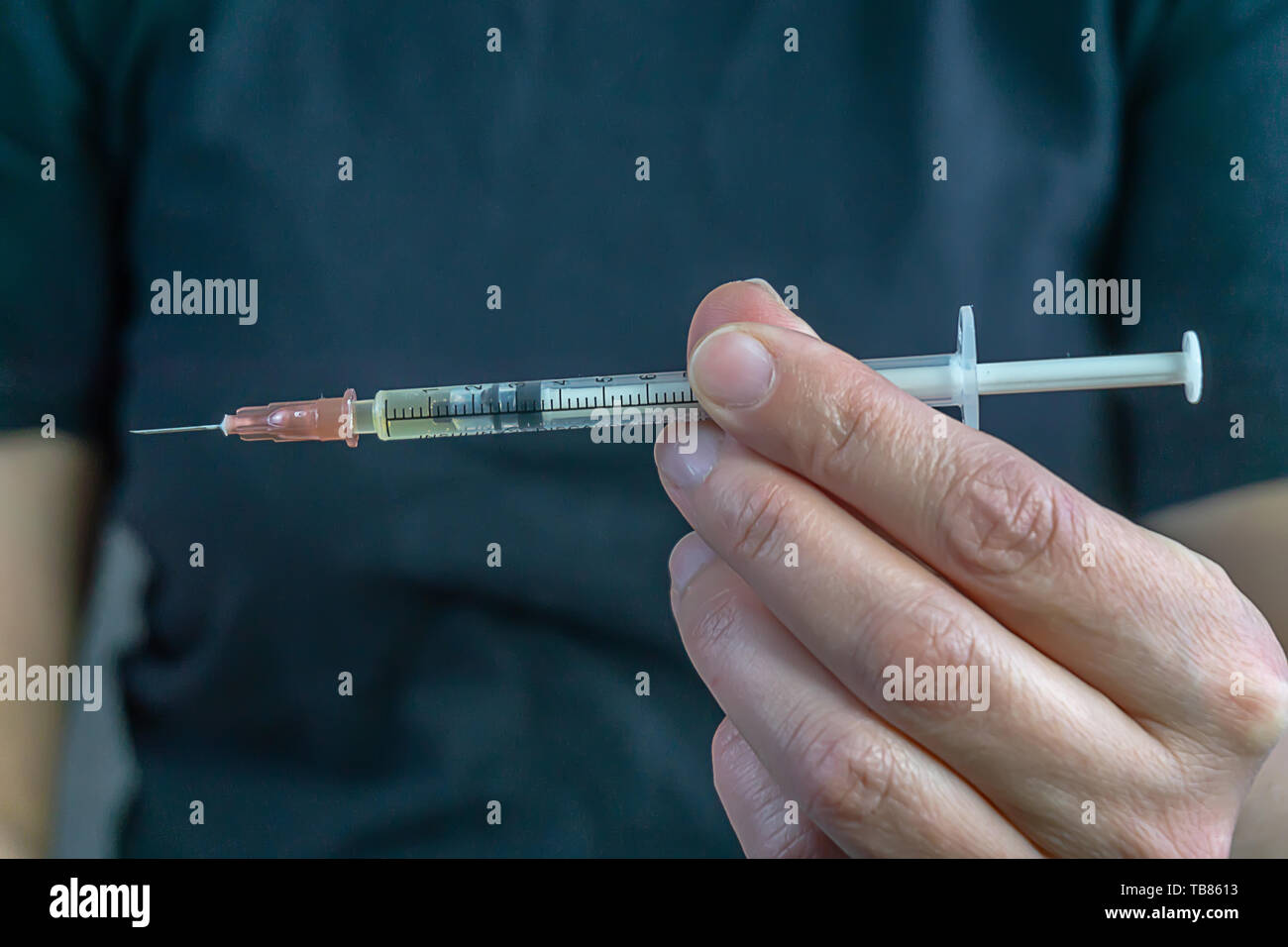 young drug addict with a syringe in her hand makes herself an injection ...