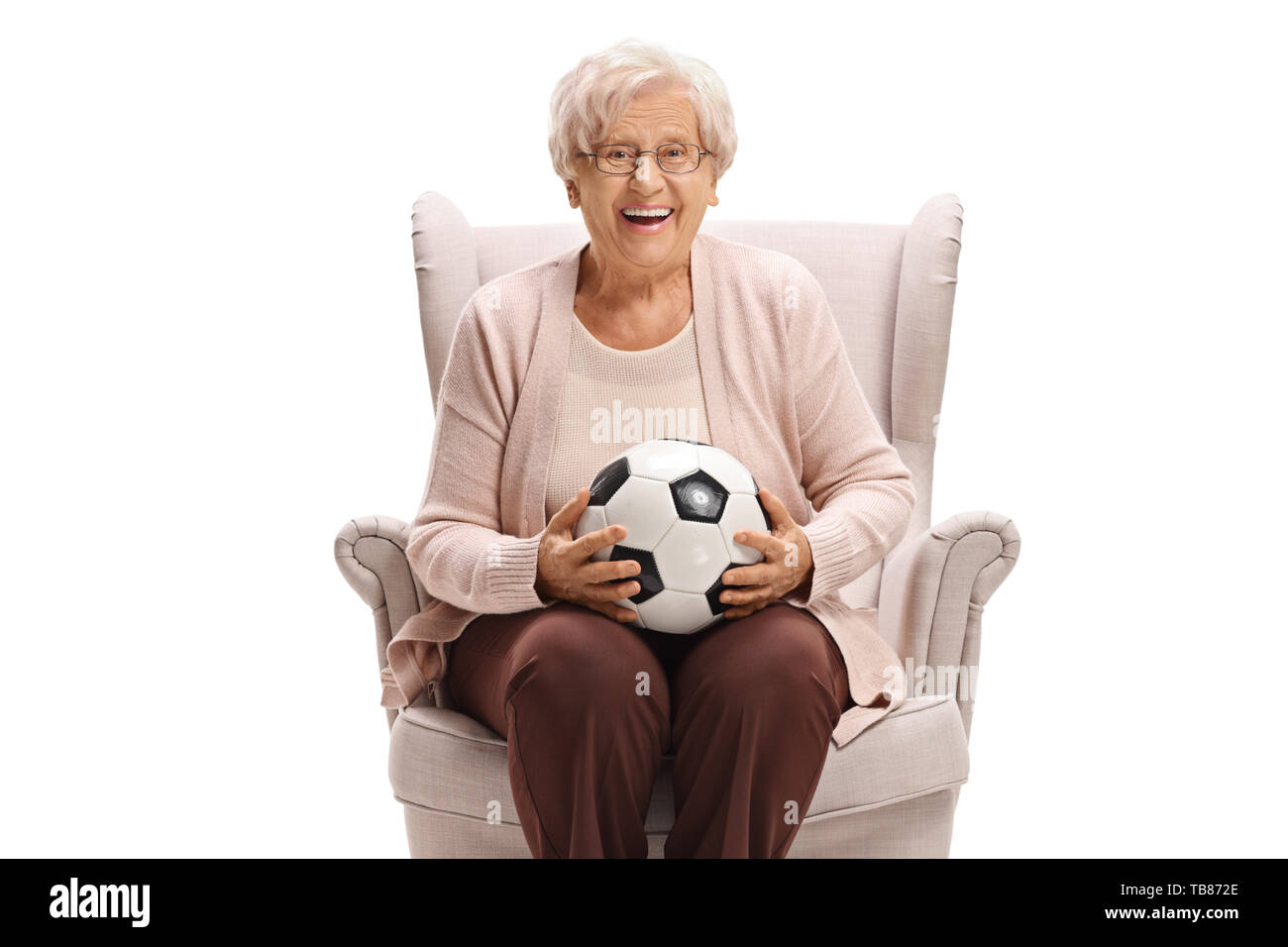 Senior woman with a football sitting in an armchair isolated on white ...