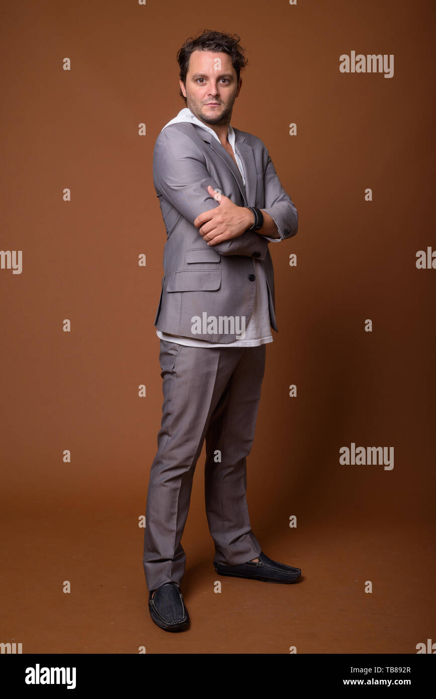 Studio shot of Italian businessman wearing suit against brown ...