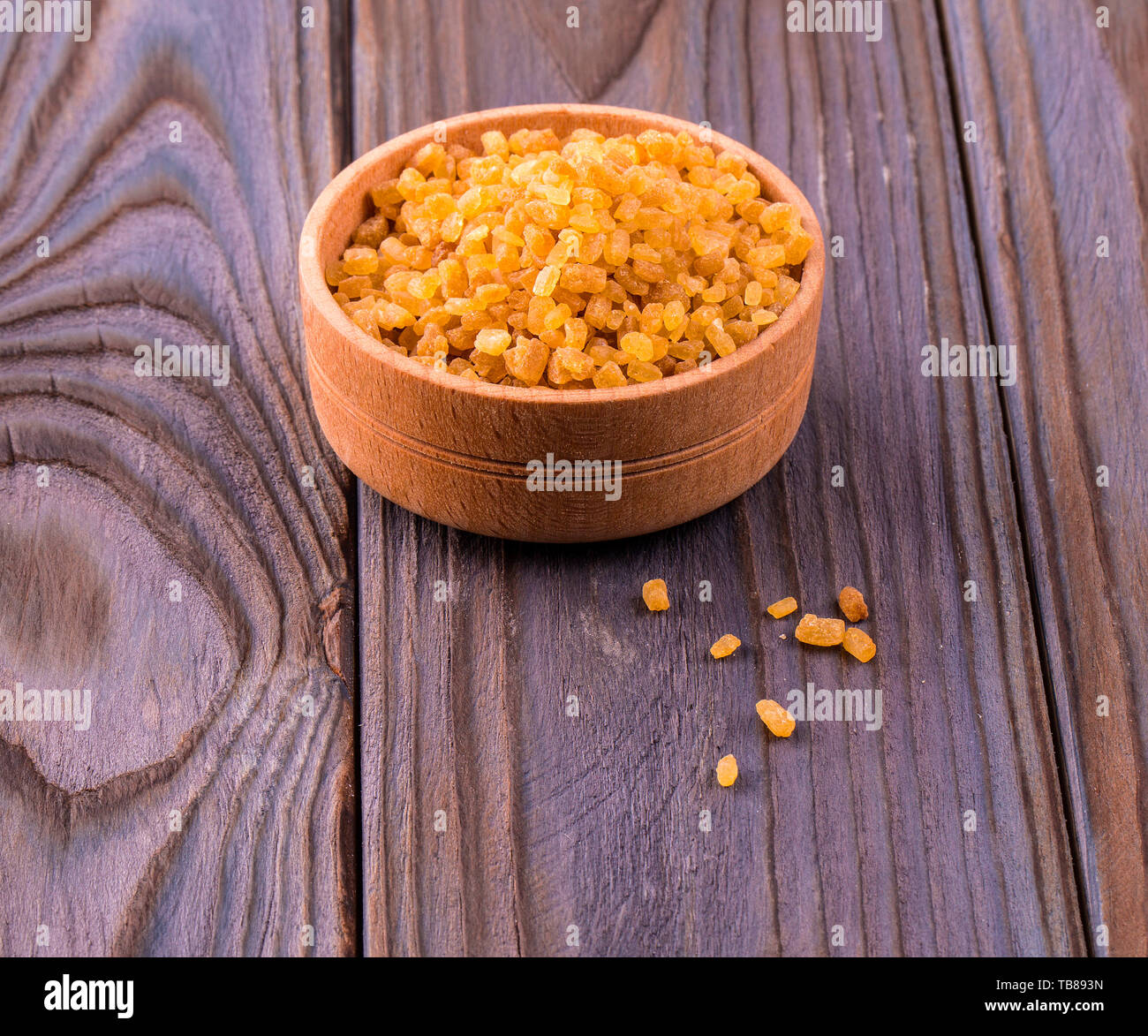 Small wooden round bowl full of brown cane sugar on wooden background ...