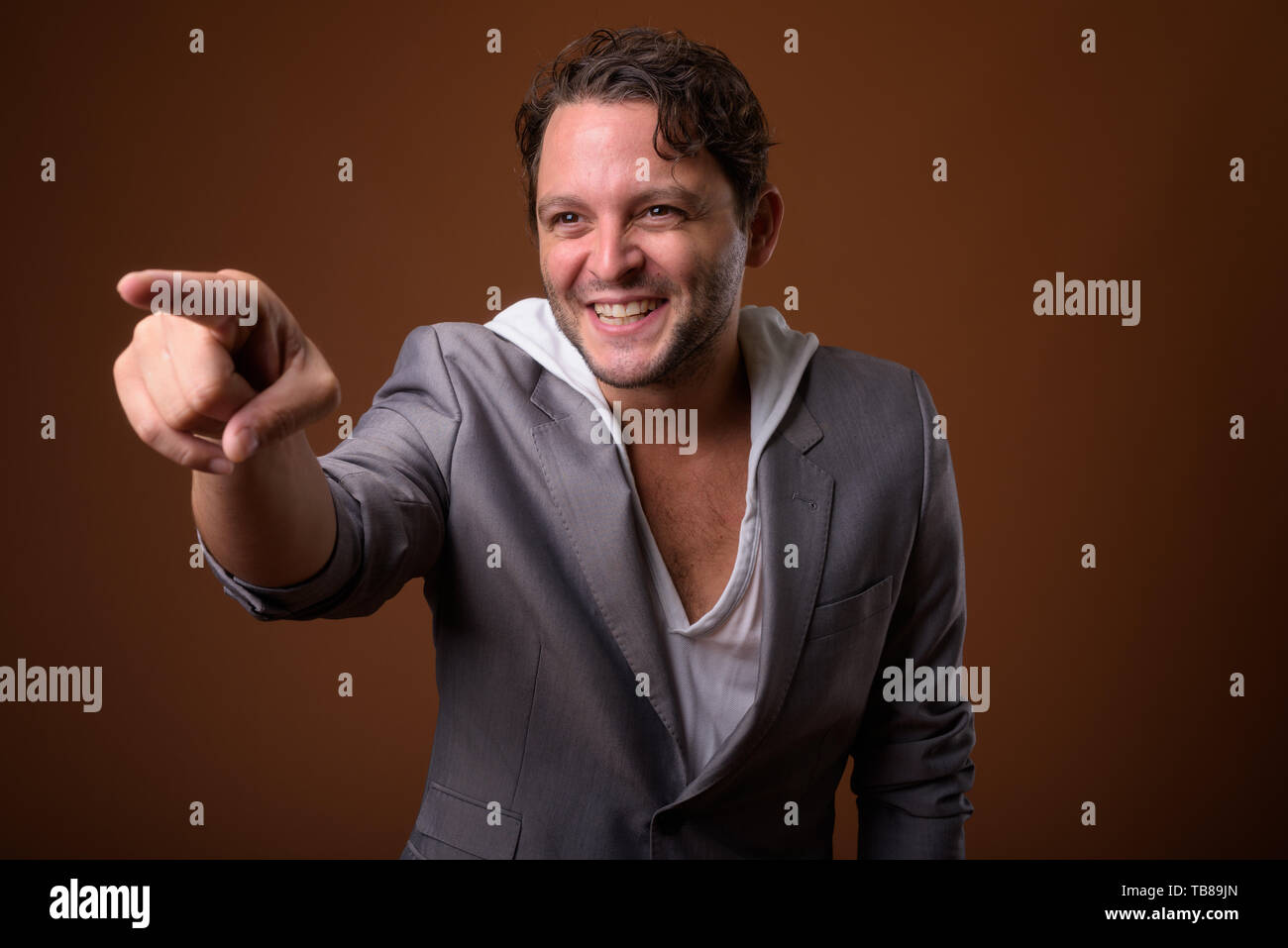 Studio shot of Italian businessman wearing suit against brown ...