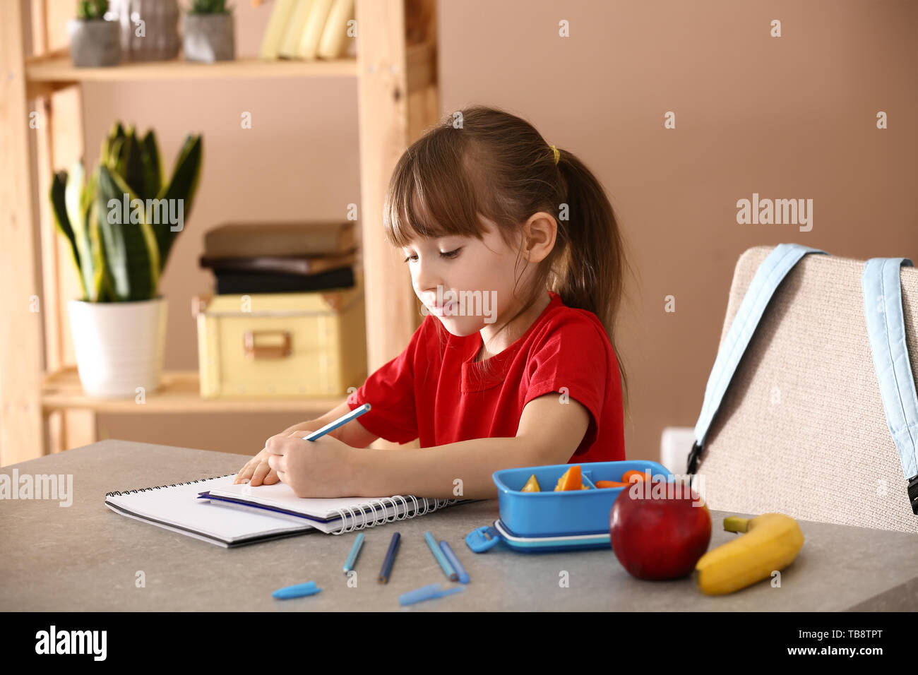 Little girl with lunch box sitting in classroom Stock Photo - Alamy
