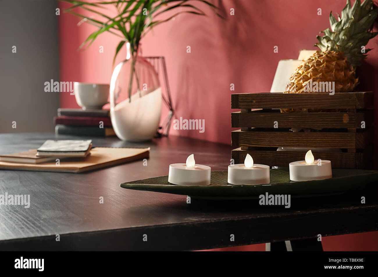 Plate with candles on dark table in room Stock Photo - Alamy