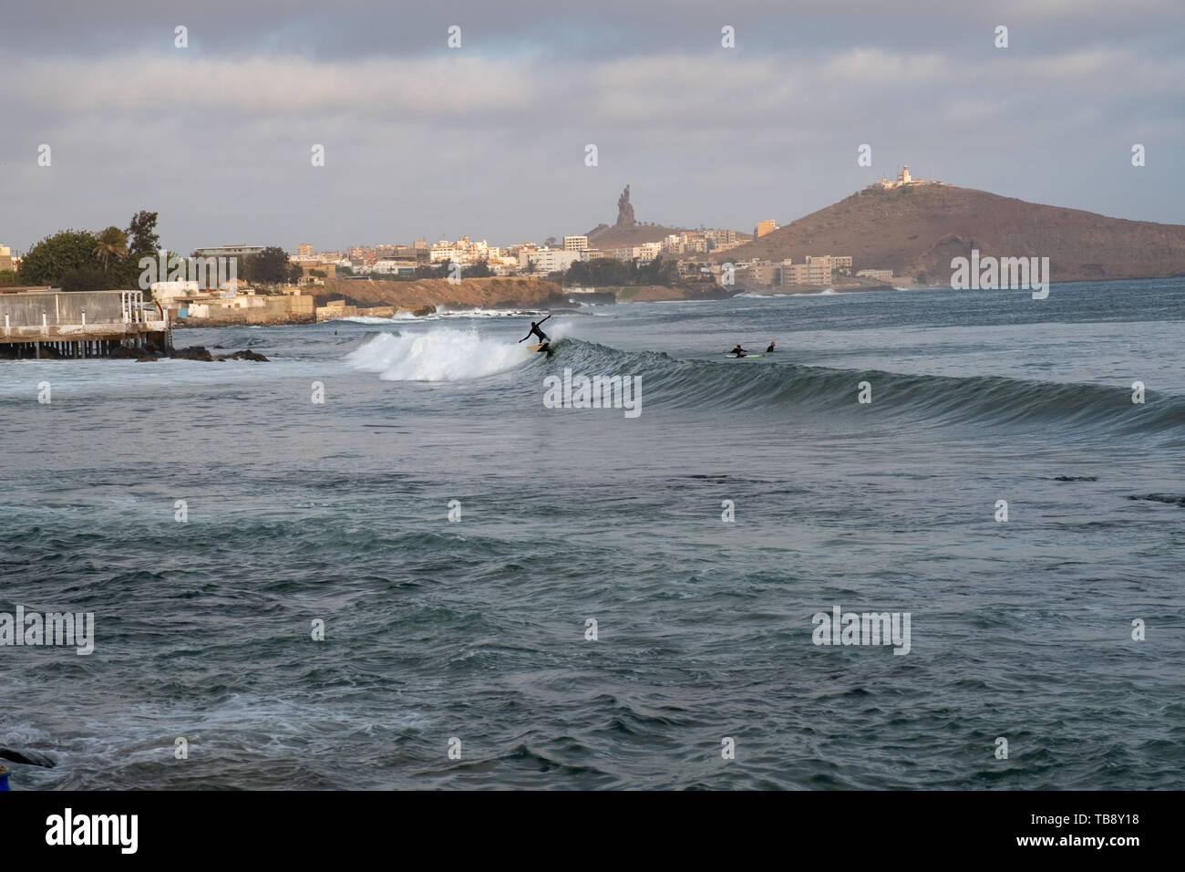 People surf on a beach in Dakar, Senegal, with the African Renaissance ...