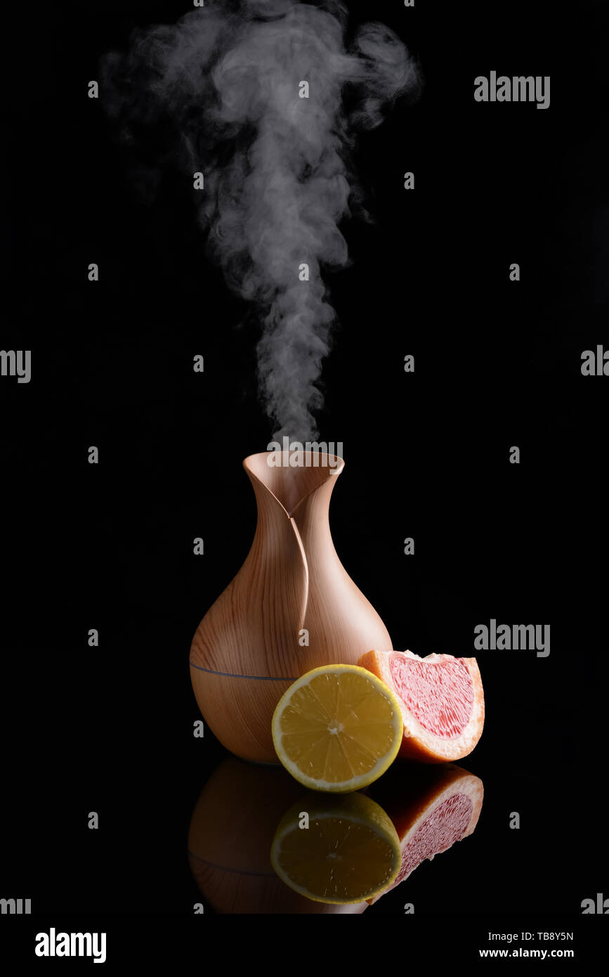 Aroma oil diffuser and citrus fruits on dark background Stock Photo - Alamy