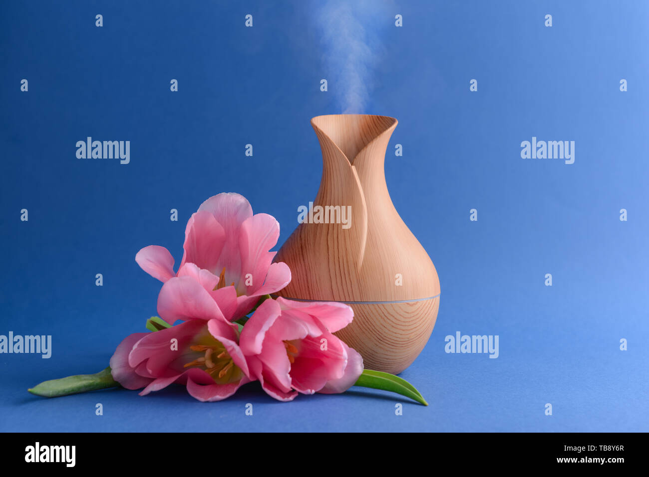 Aroma oil diffuser and flowers on color background Stock Photo - Alamy