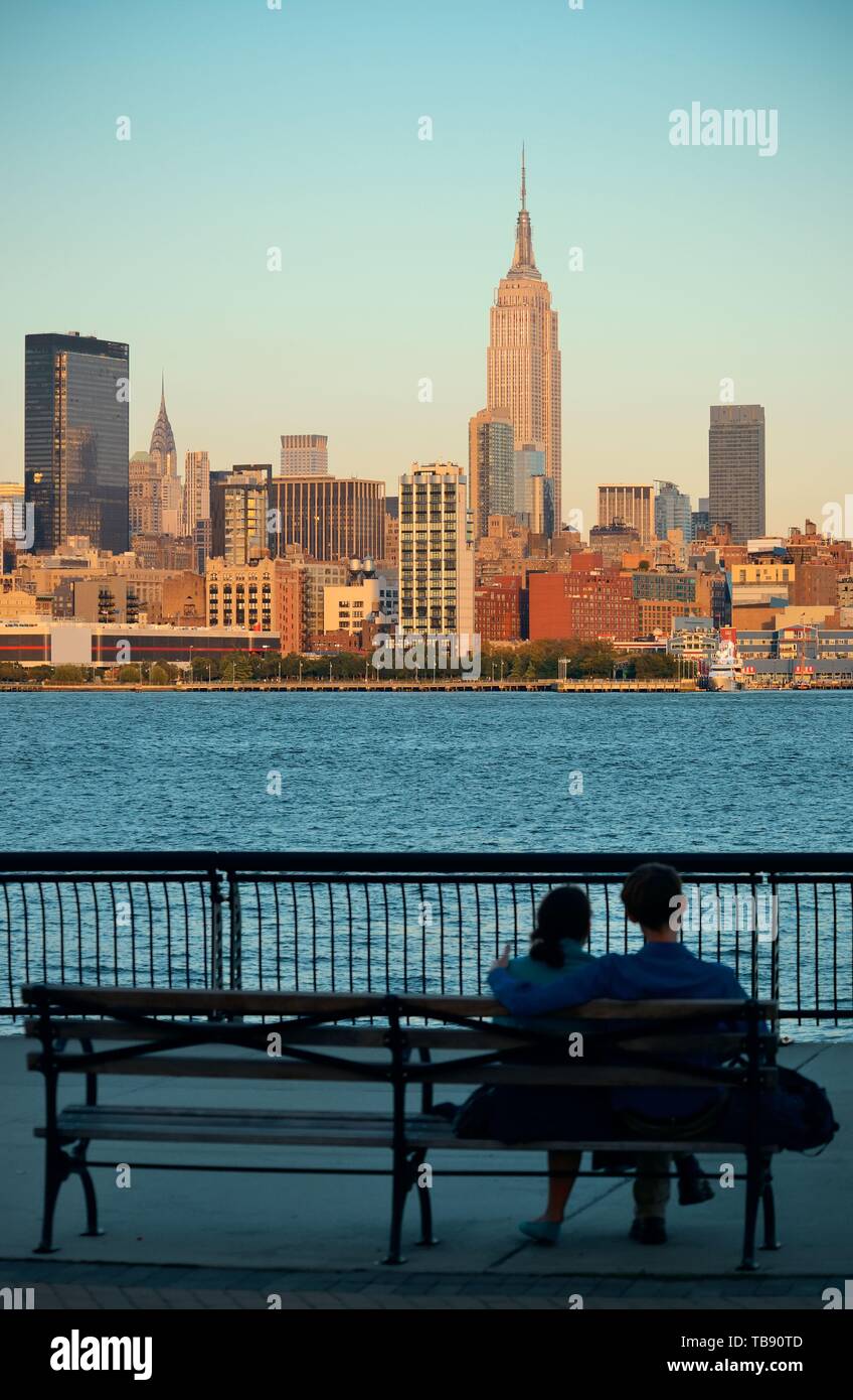 Couple rest on bench watching New York City skyscrapers Stock Photo - Alamy