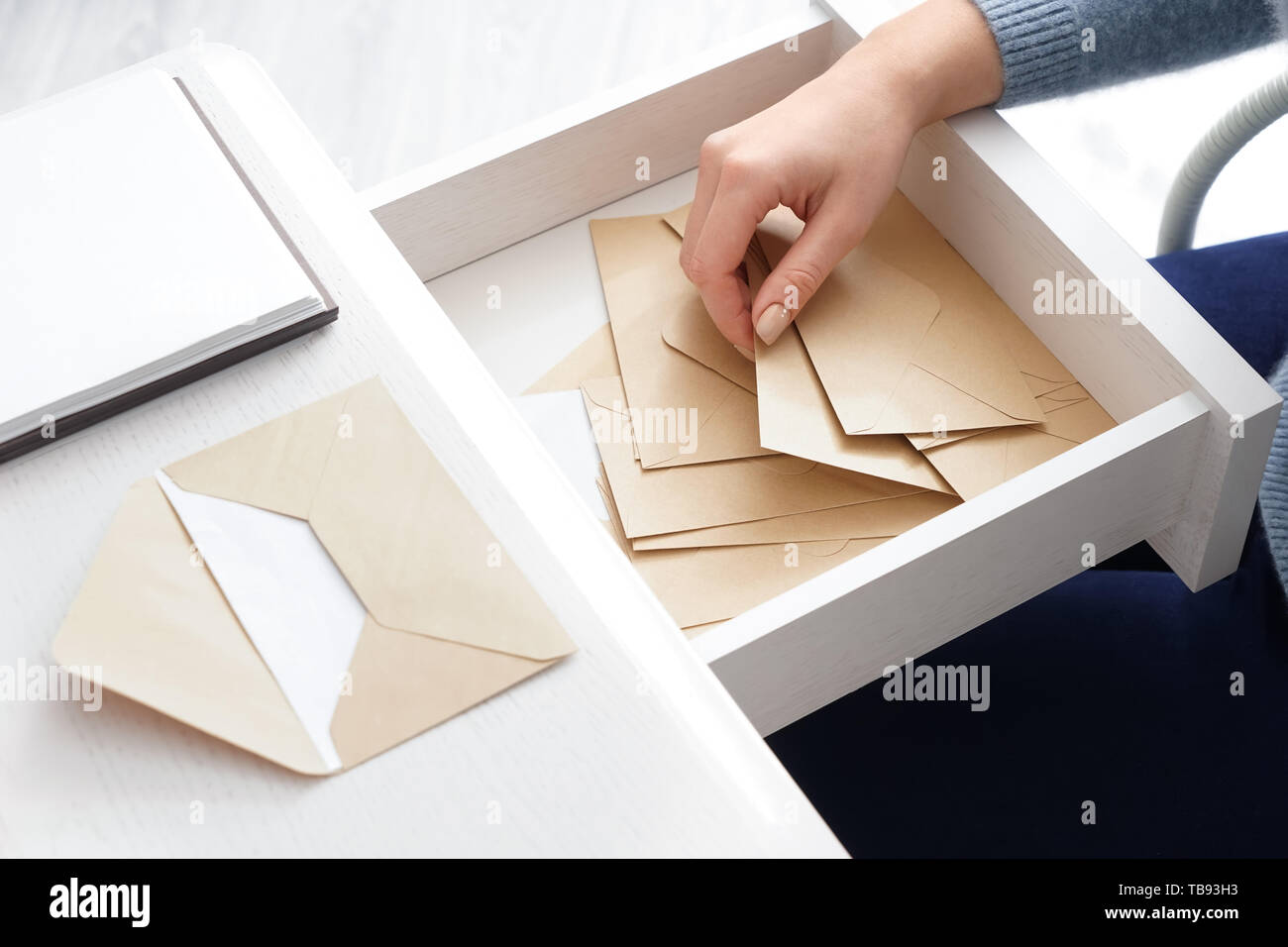 Young woman taking envelope from table drawer Stock Photo - Alamy