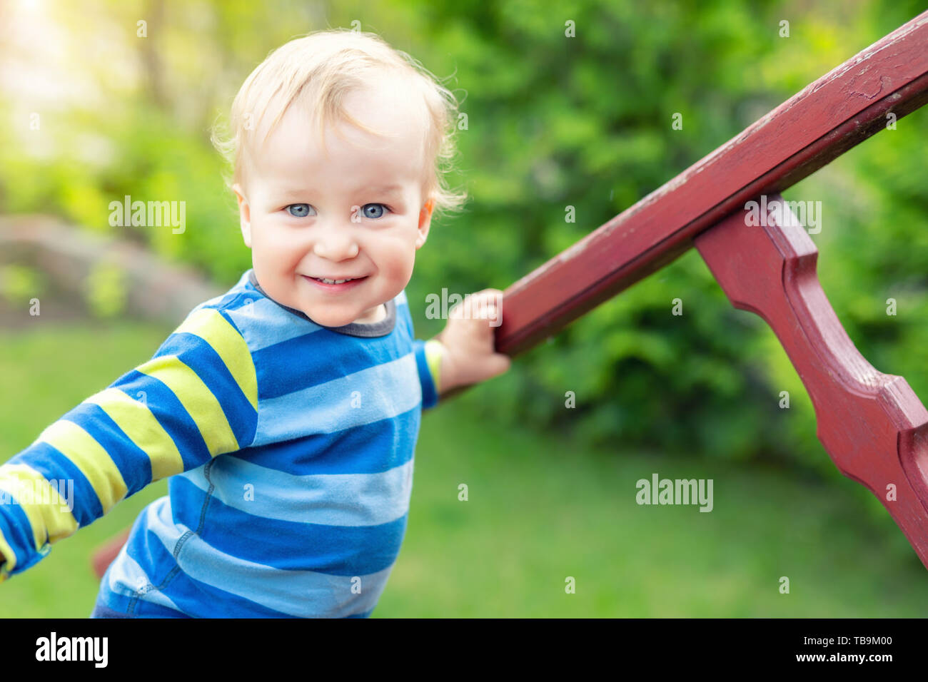 Portrait of cute mischievous caucasian blond baby boy holding wooden ...