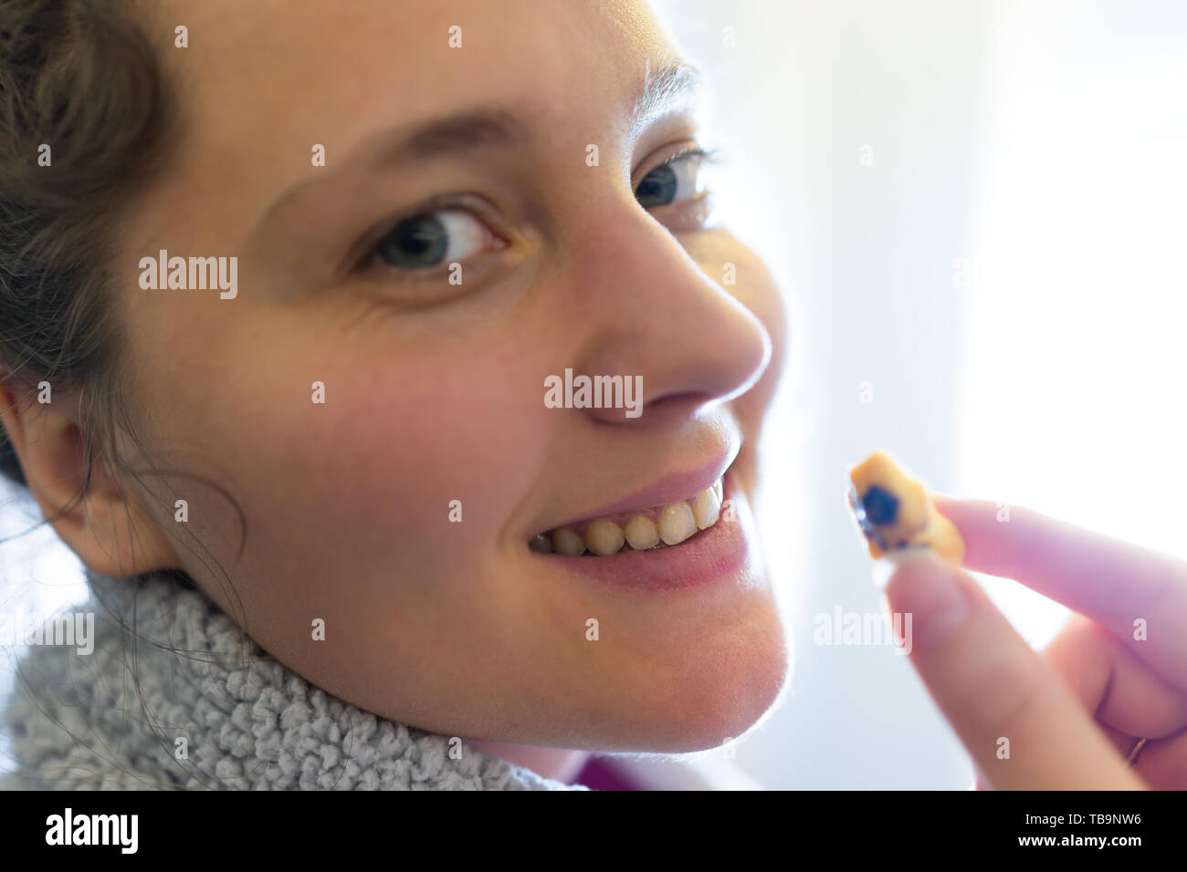 Closeup of young happy woman face eating Japanese snack food rice ...
