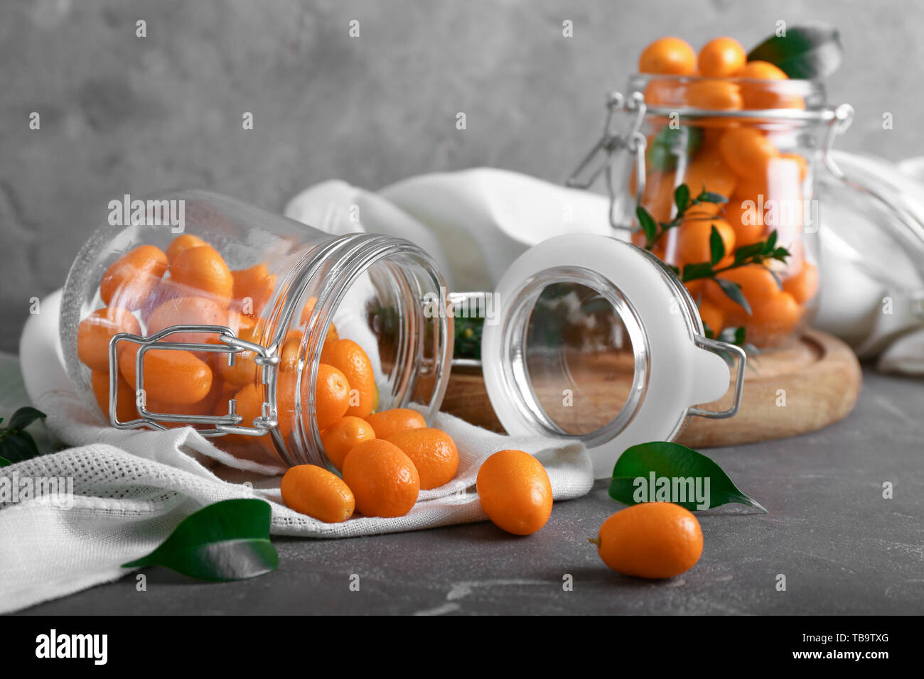 Overturned glass jar with delicious kumquat fruit on table Stock Photo ...