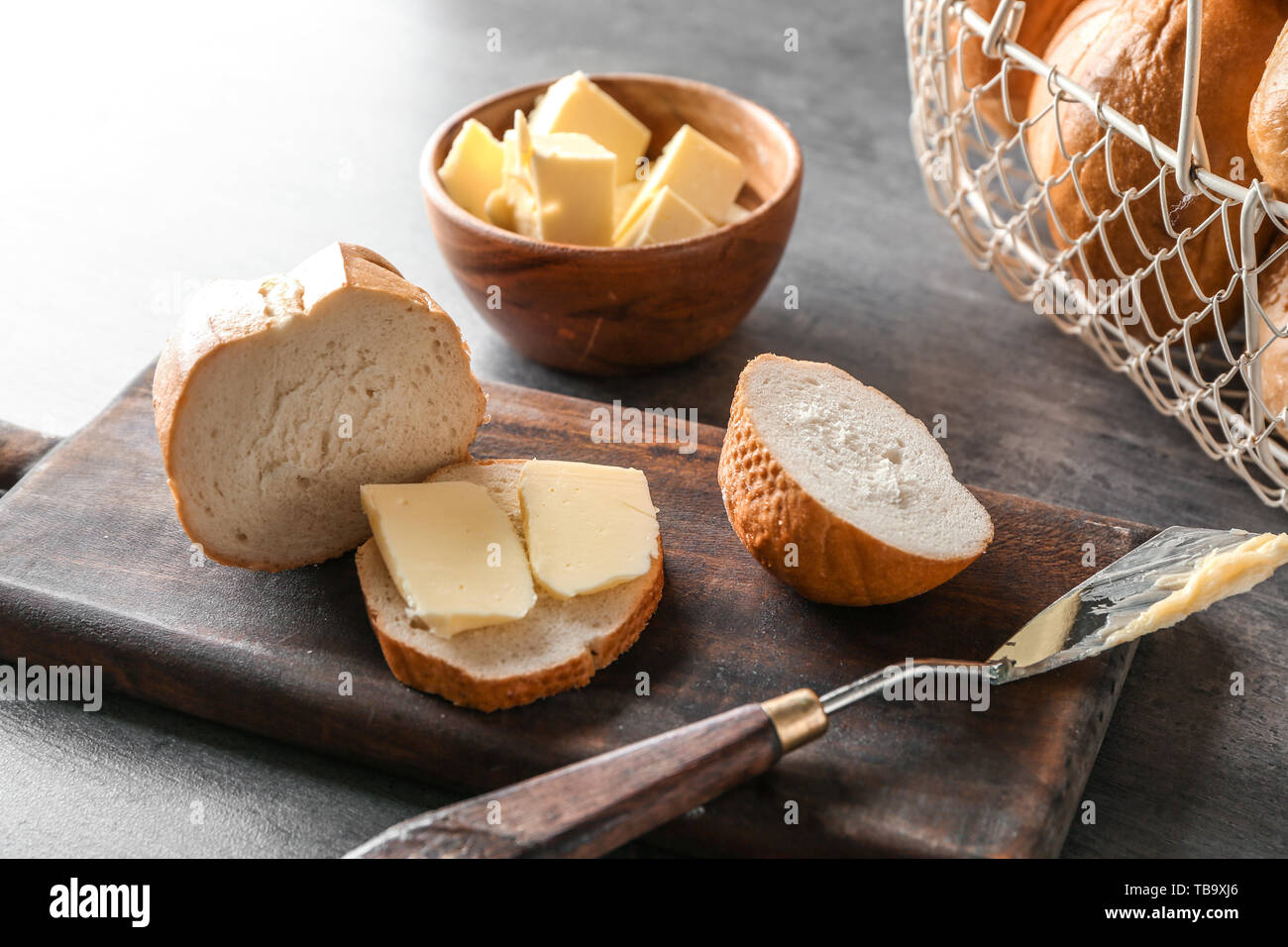 Board with cut fresh bread and butter on grey table Stock Photo - Alamy