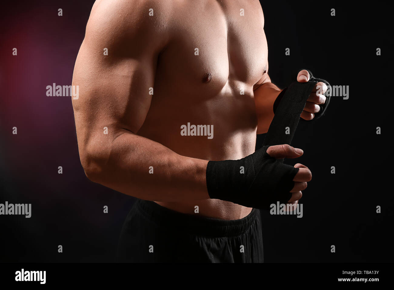 Attractive sportsman winding wrist band against dark background Stock ...