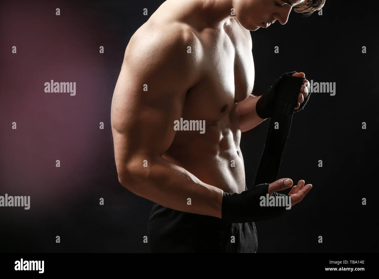 Attractive sportsman winding wrist band against dark background Stock ...