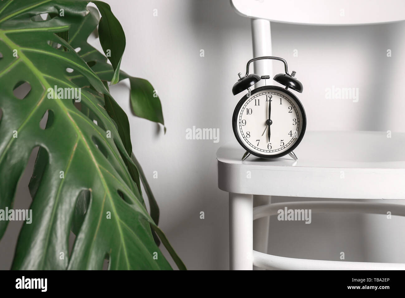 Alarm clock on chair against white background Stock Photo - Alamy
