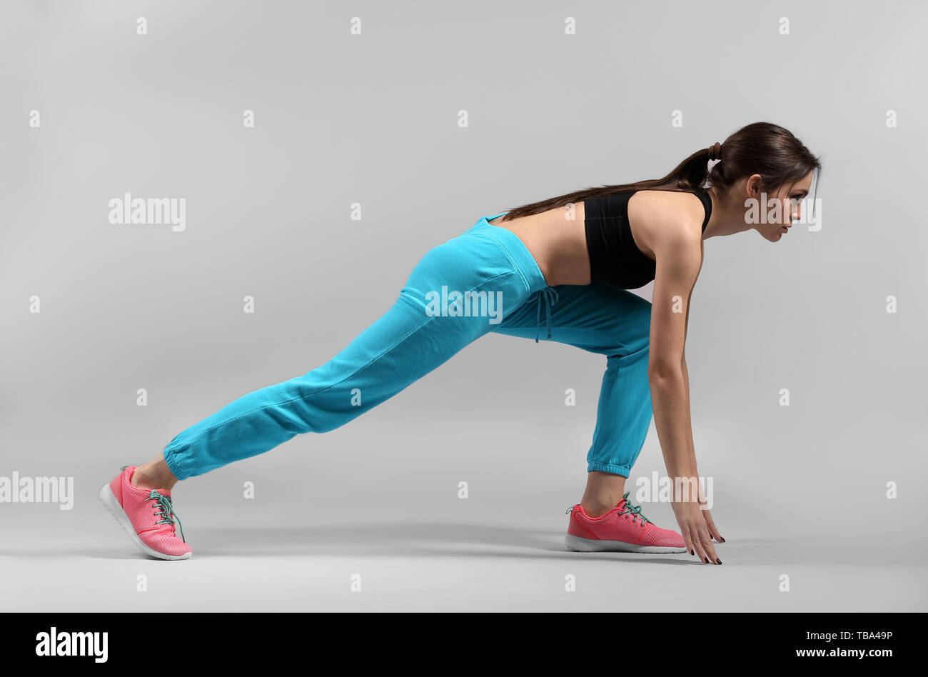 Sporty young woman in crouch start position against light background ...