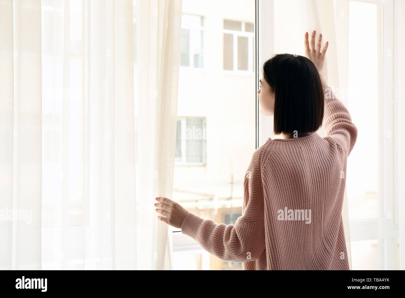 Young woman opening curtains in morning Stock Photo - Alamy