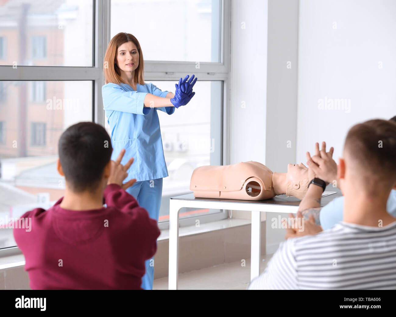 Instructor demonstrating CPR on mannequin at first aid training course ...