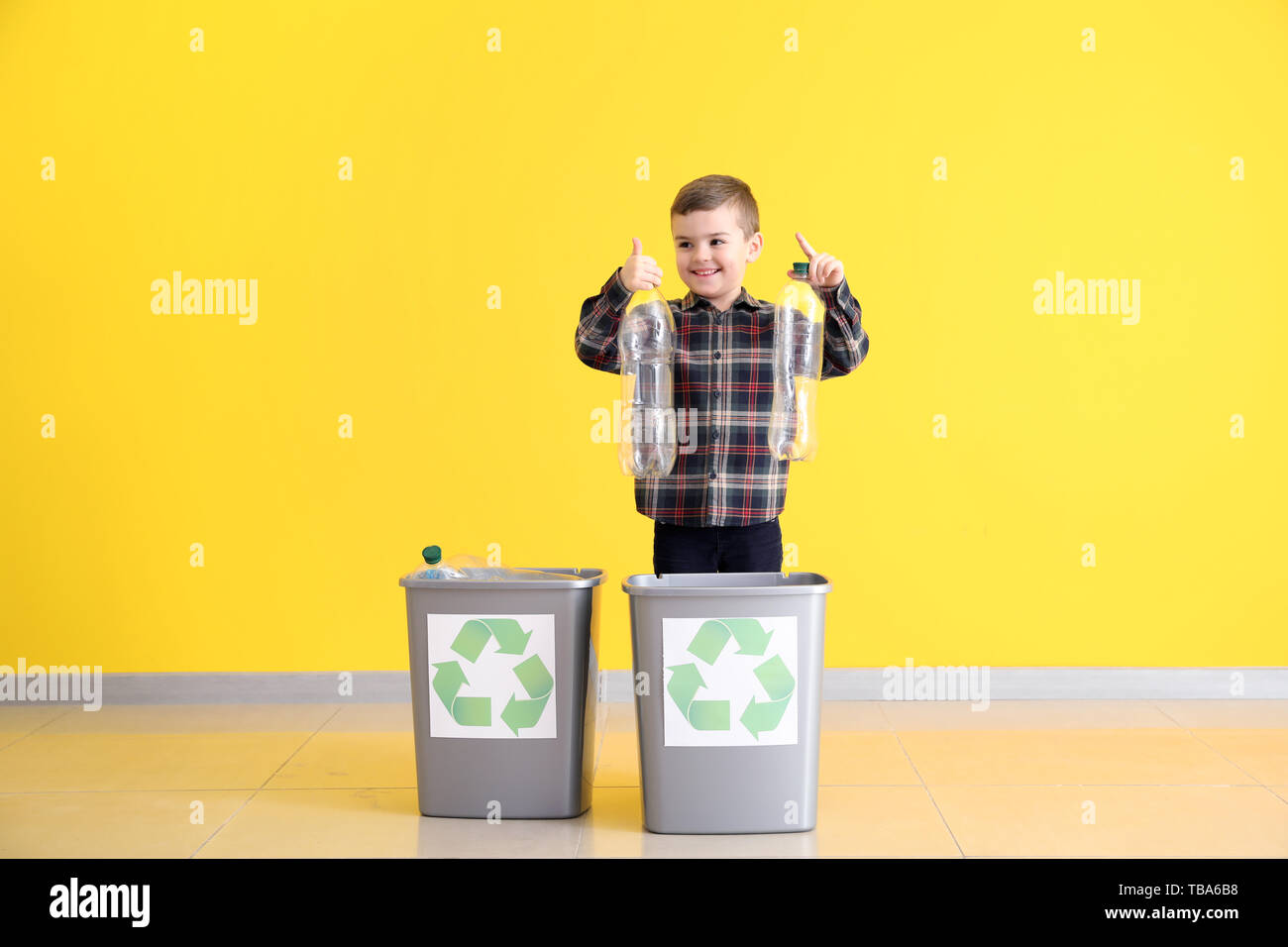 Little boy throwing garbage into trash bins near color wall. Concept of ...