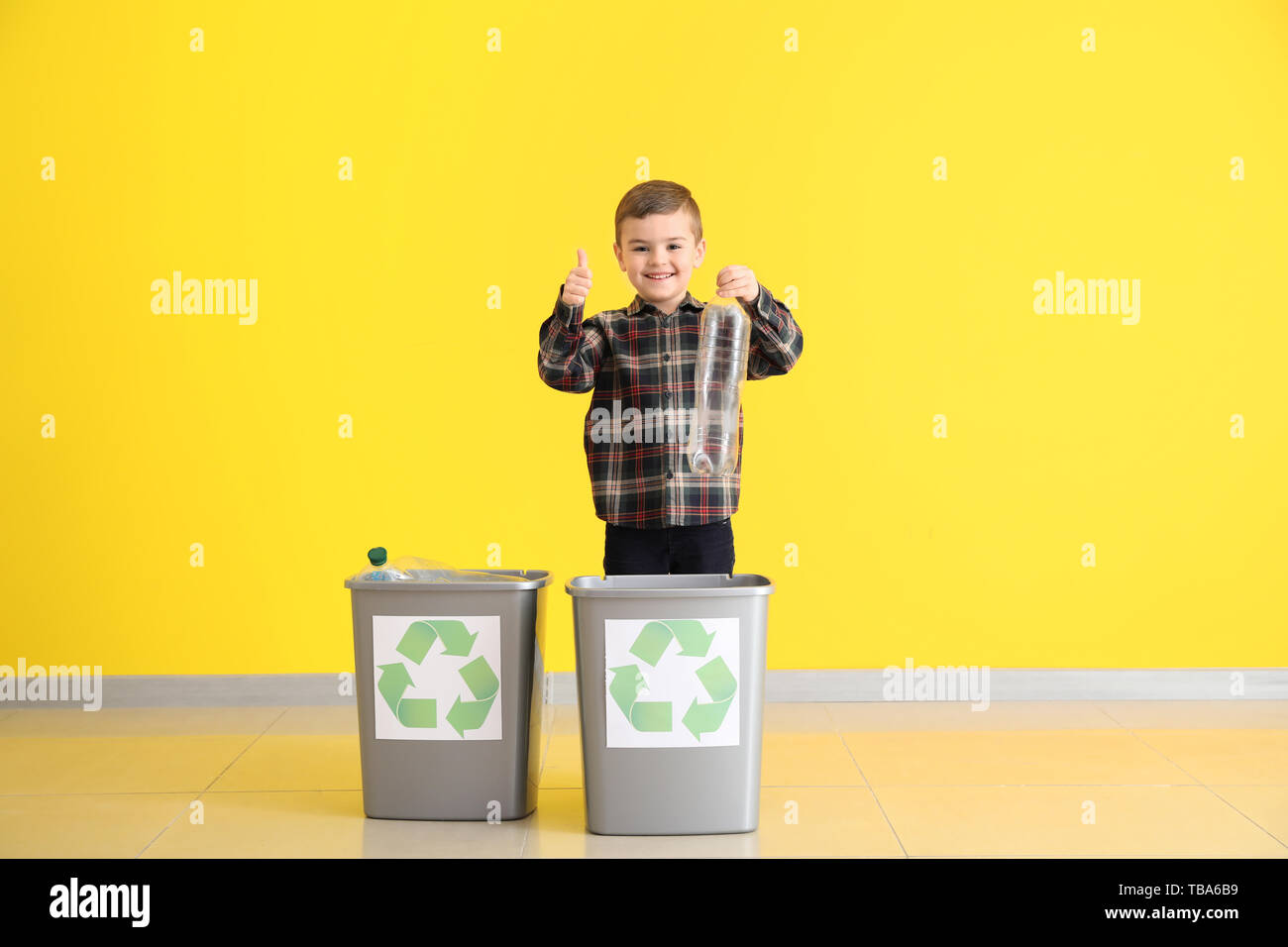 Little boy throwing garbage into trash bins near color wall. Concept of ...