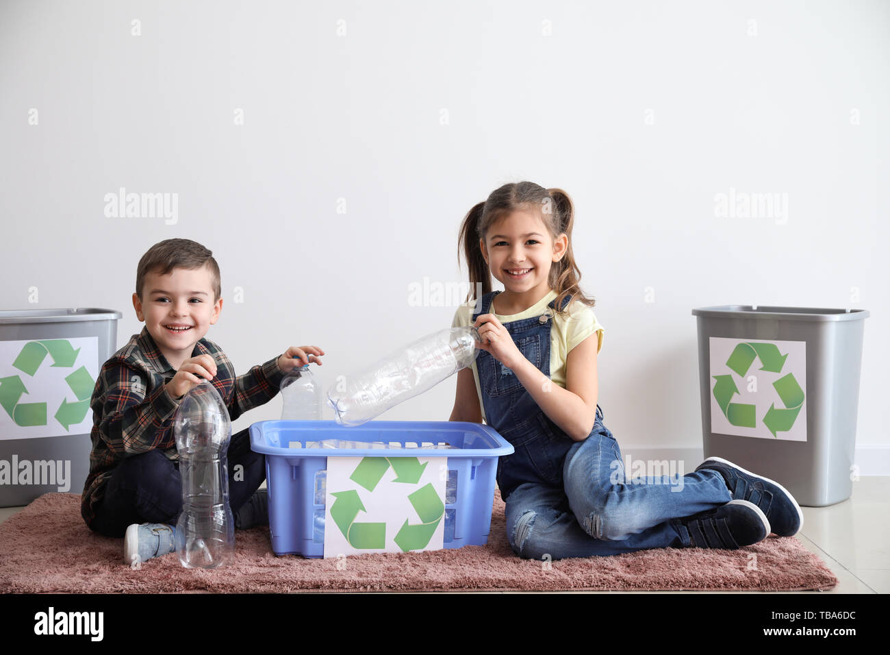 Little children sorting garbage near white wall. Concept of recycling ...