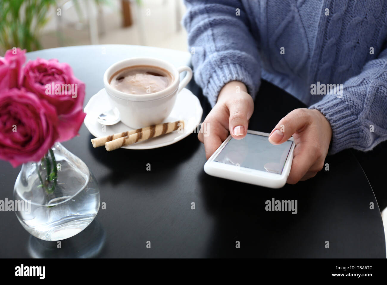 Young woman with mobile phone sitting at table Stock Photo - Alamy