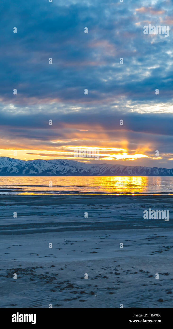 frame Vertical Golden sun reflected on the glistening lake with sandy ...