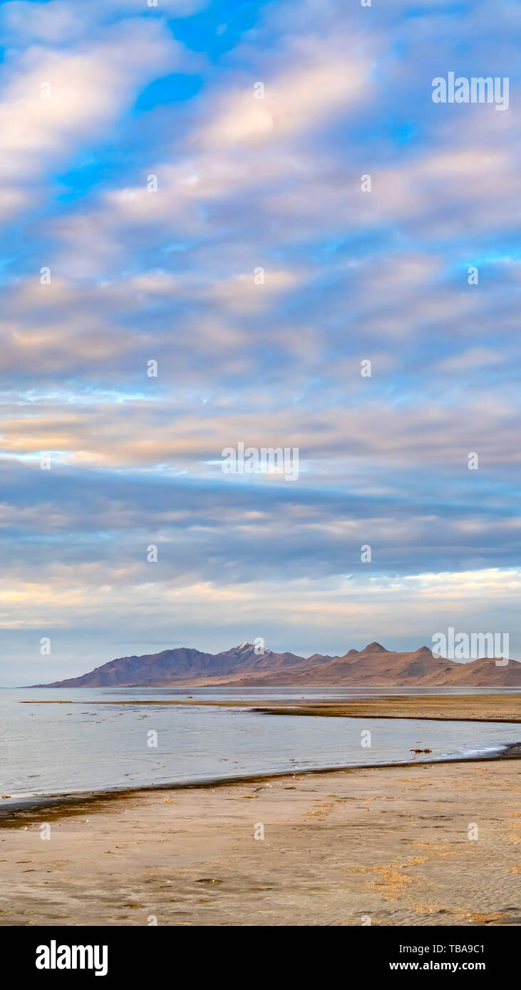 frame Vertical frame Gleaming lake with sandy shore and rugged mountain ...