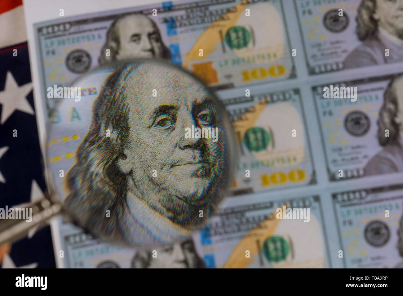 US dollars and magnifying glass on a print counterfeiting fake money ...