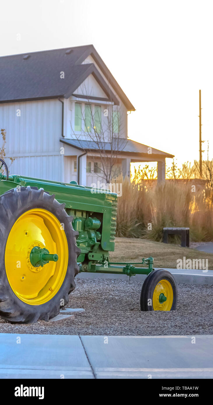 Vertical frame Replica of a tractor at a park with houses and sky in ...