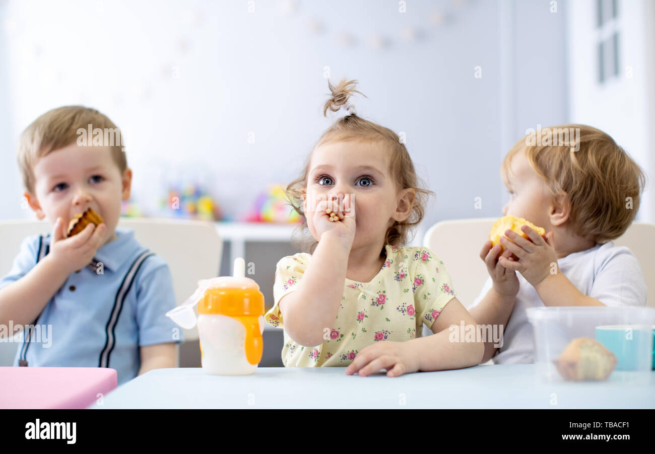Time to eat in kindergarten. Funny nursery babies have dinner Stock ...