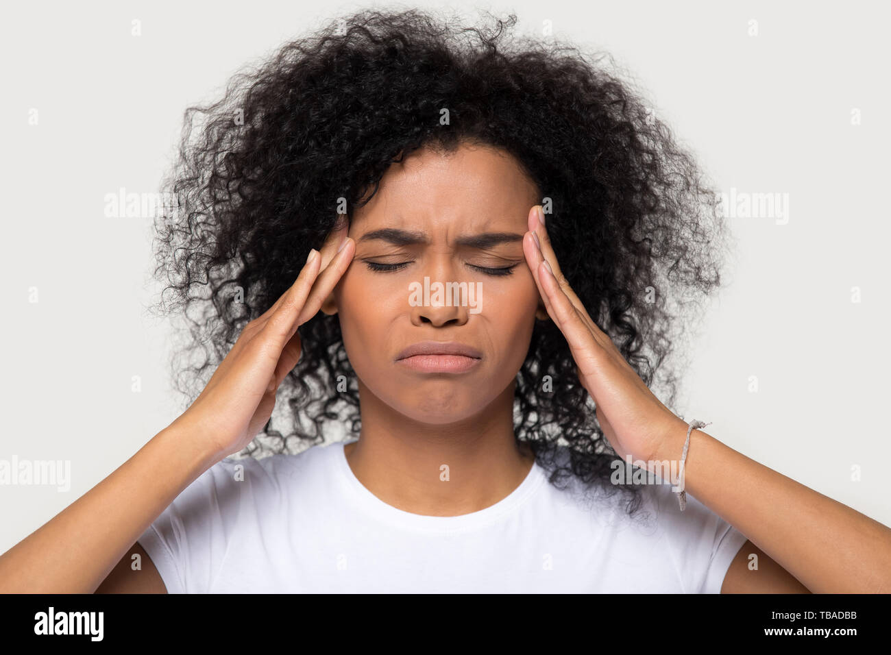Studio portrait young african female touch temples suffers from ...