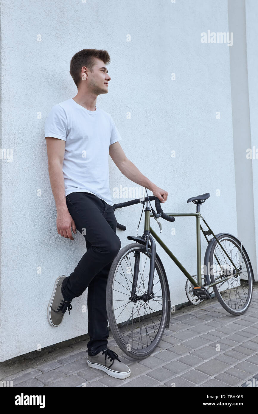 Young hipster style man posing with bicycle on the street sport style ...