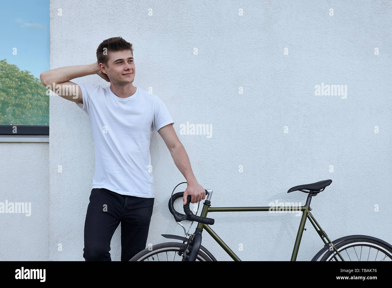 Young hipster style man posing with bicycle on the street sport style ...