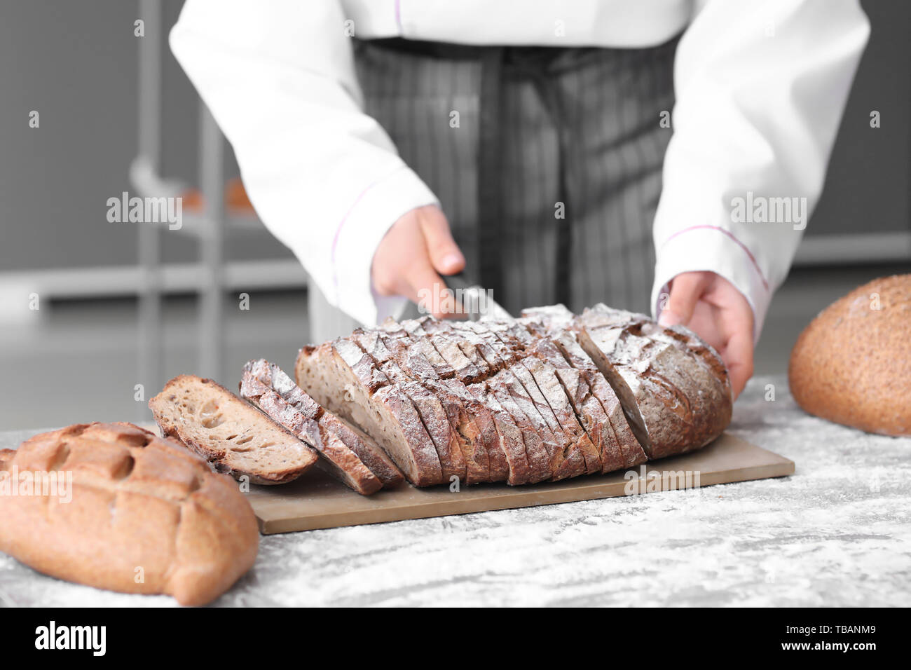 Female baker cutting fresh bread in kitchen Stock Photo - Alamy