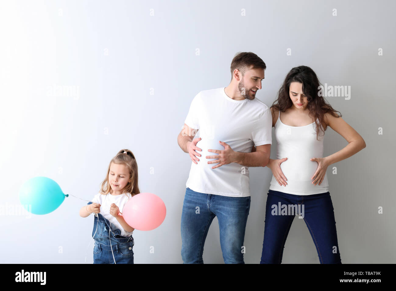 Happy family expecting baby on light background Stock Photo - Alamy