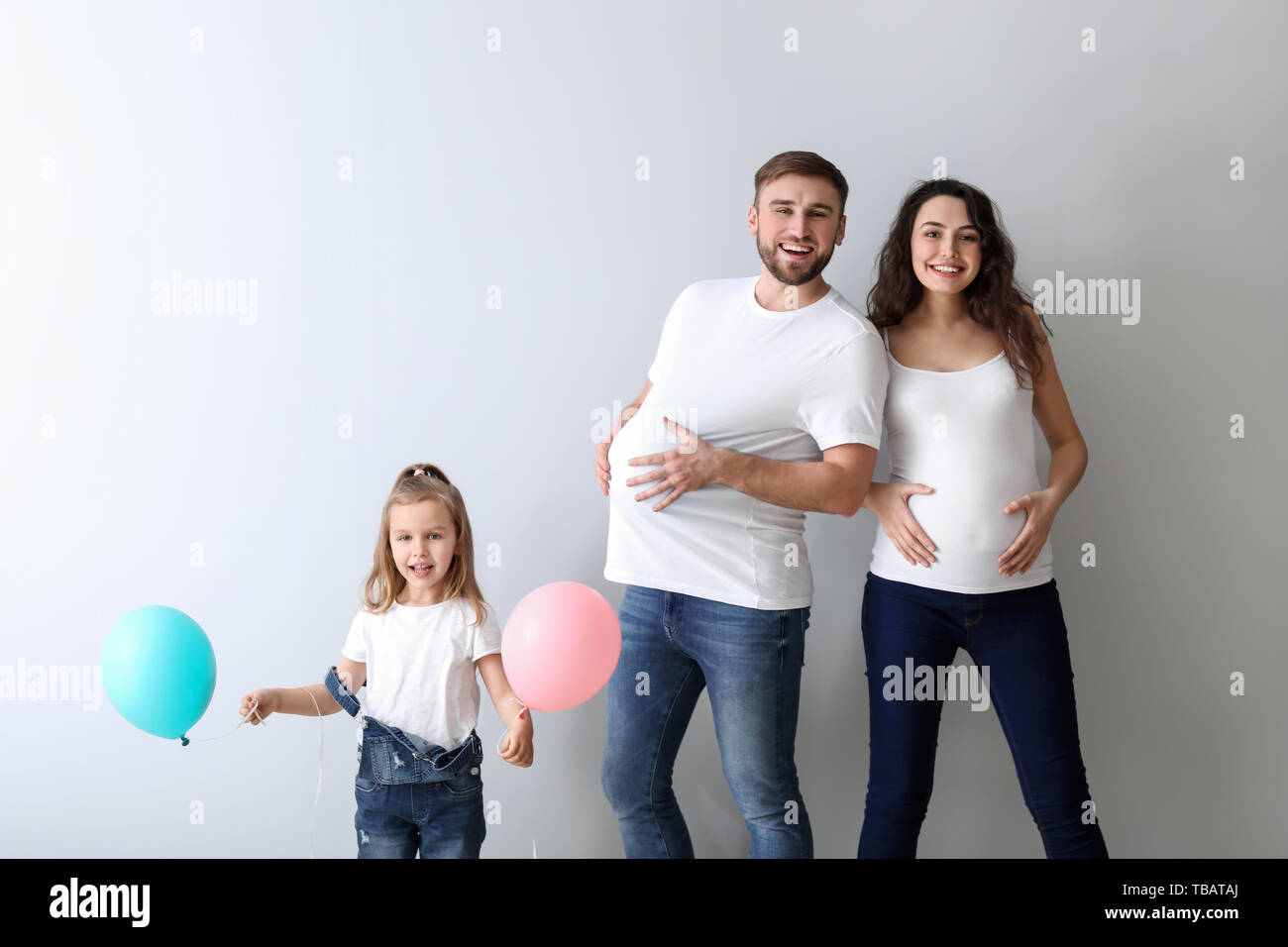 Happy family expecting baby on light background Stock Photo - Alamy