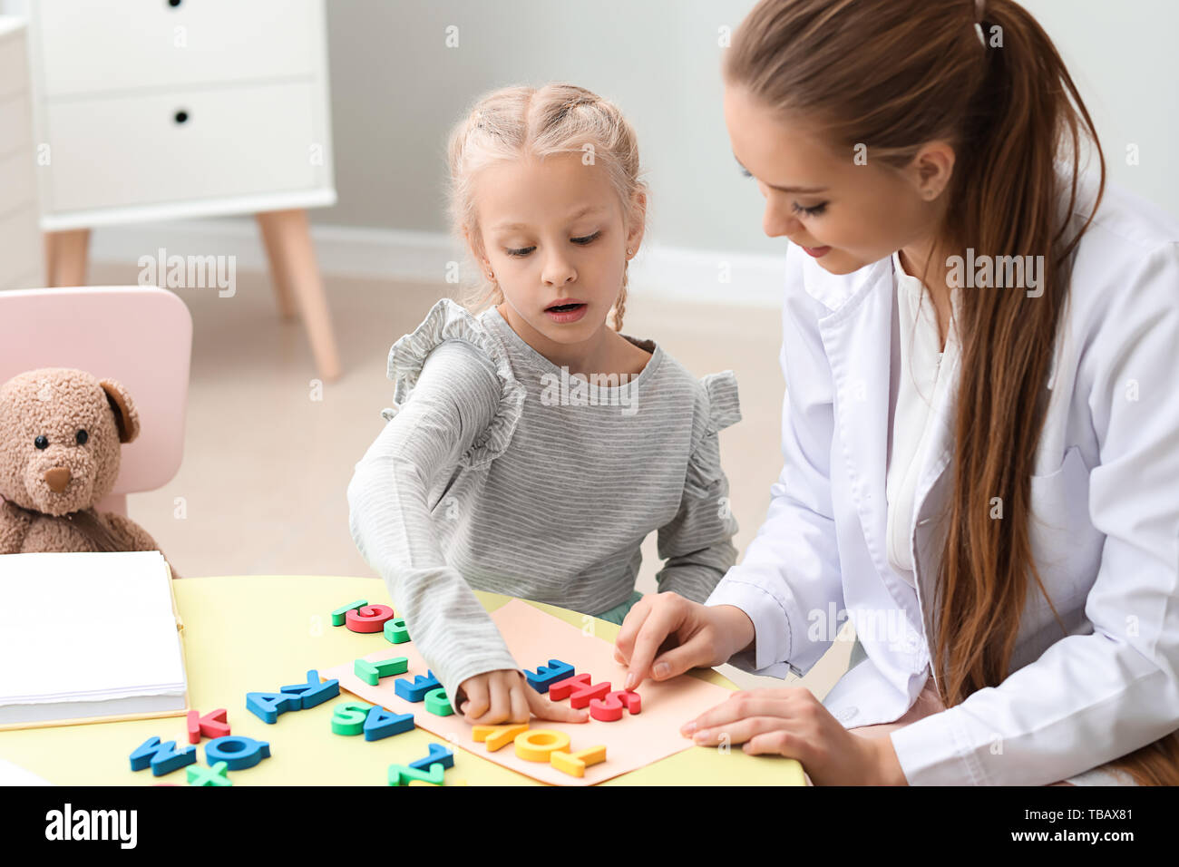 Little girl with speech therapist composing words of letters in office ...