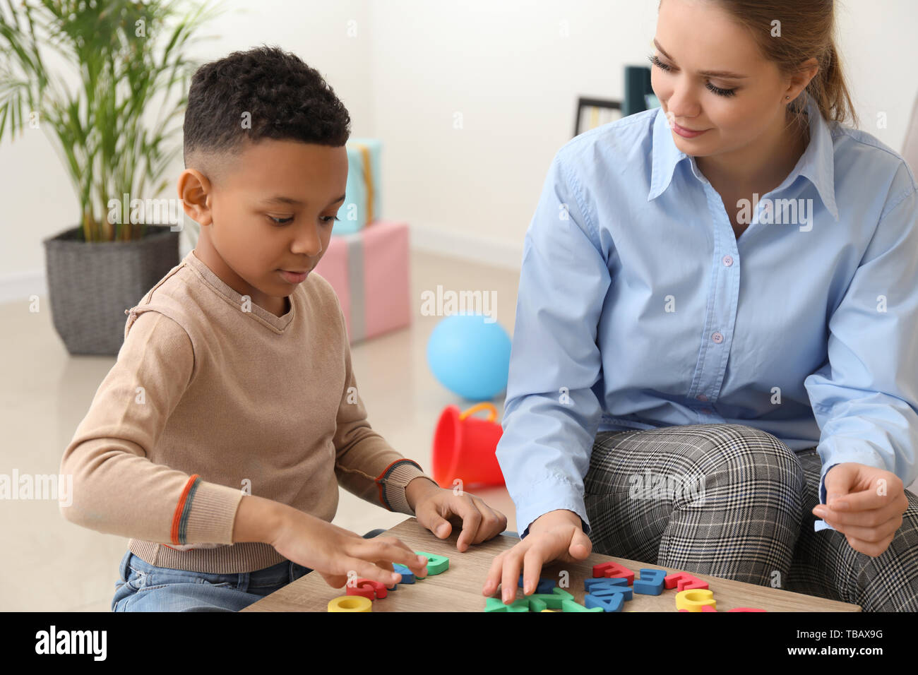 Little boy with speech therapist composing words of letters in office ...