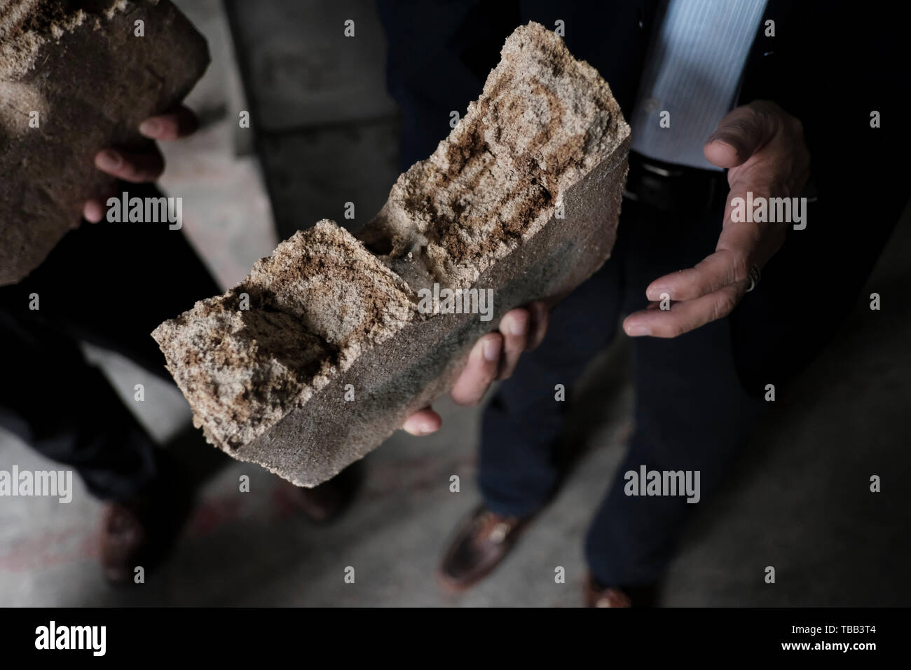 Man holds a fermented wheat brick after it was stores in the ...