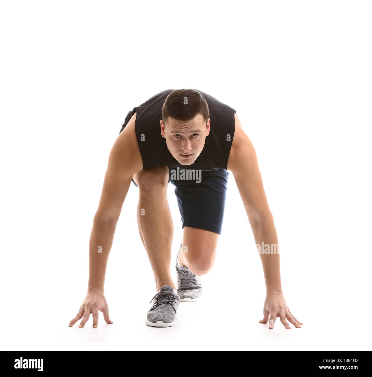 Sporty young man in crouch start position against white background ...