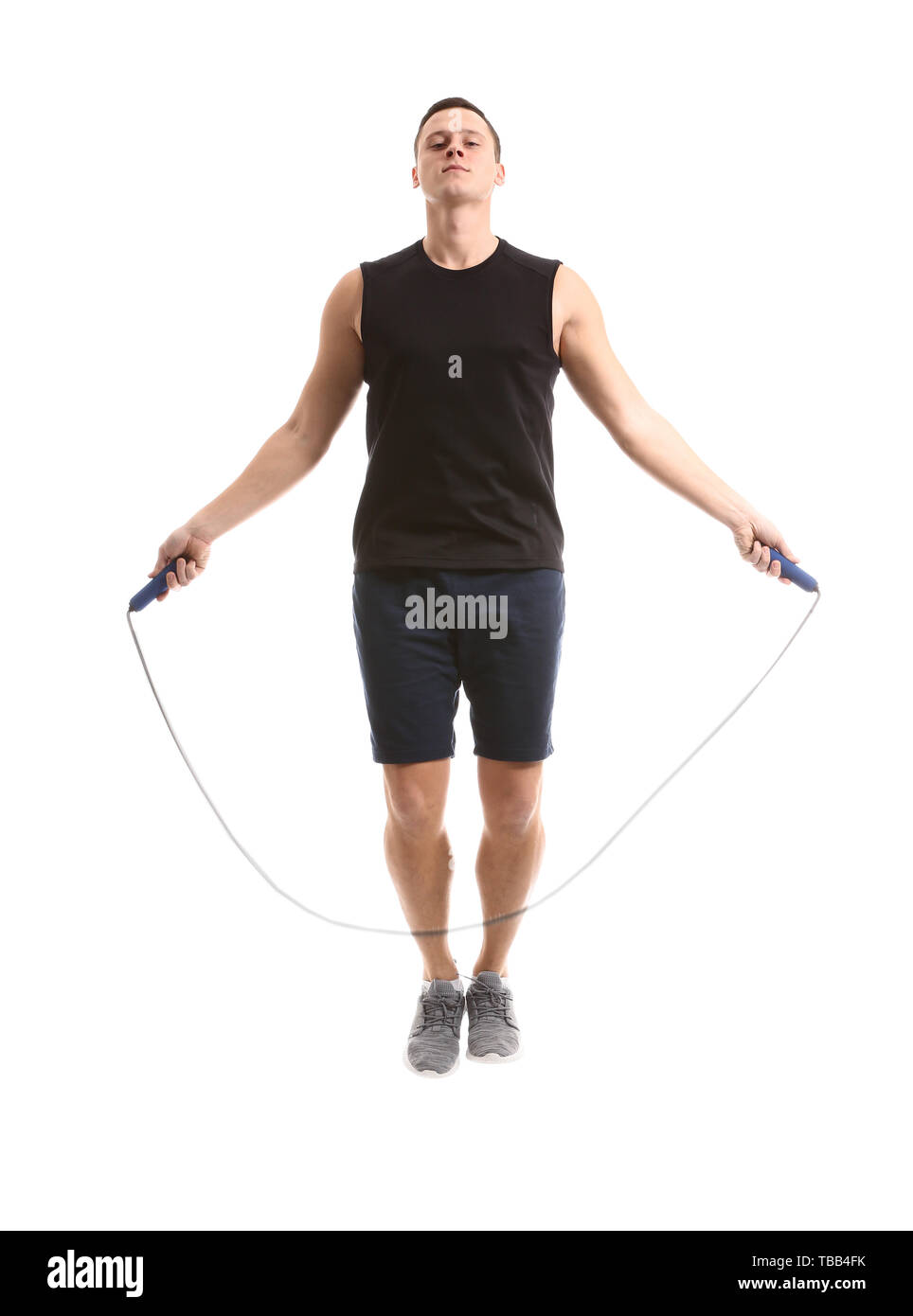Sporty young man jumping rope against white background Stock Photo - Alamy